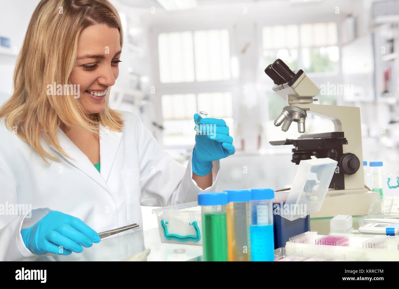 Female scientist in lab coat and protective gloves ilaughts while ...