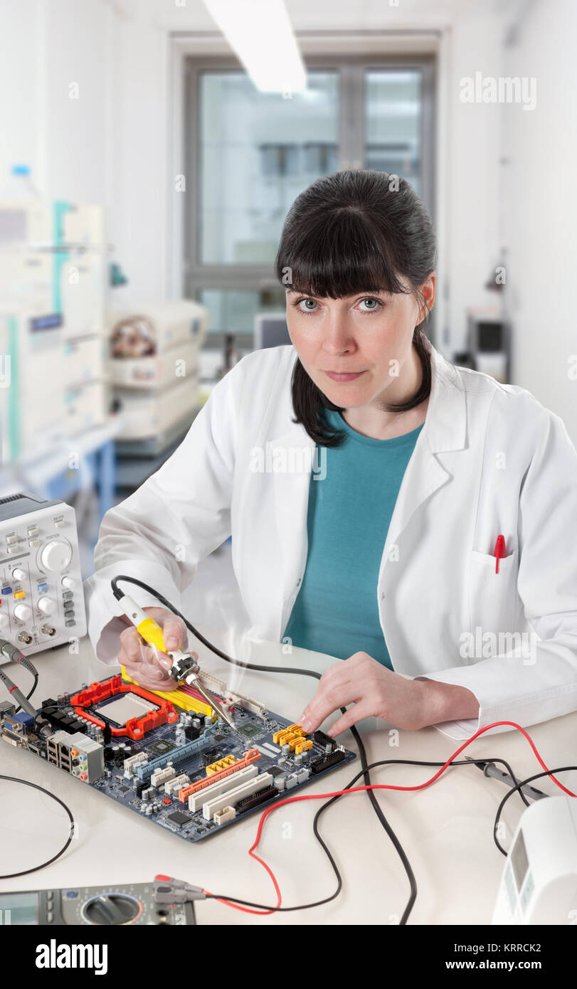 Young female tech soldering a circuit board in modern laboratory looks ...