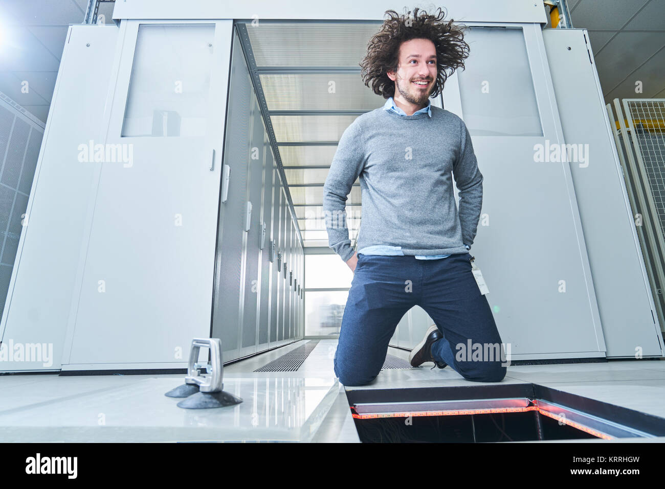 Young man fixing something in the floor hatch. Data center. Servers ...