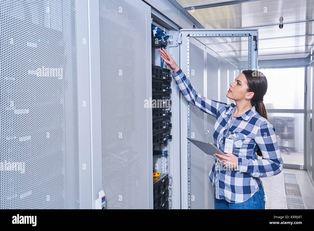 female technician working on server maintenance in white server room ...
