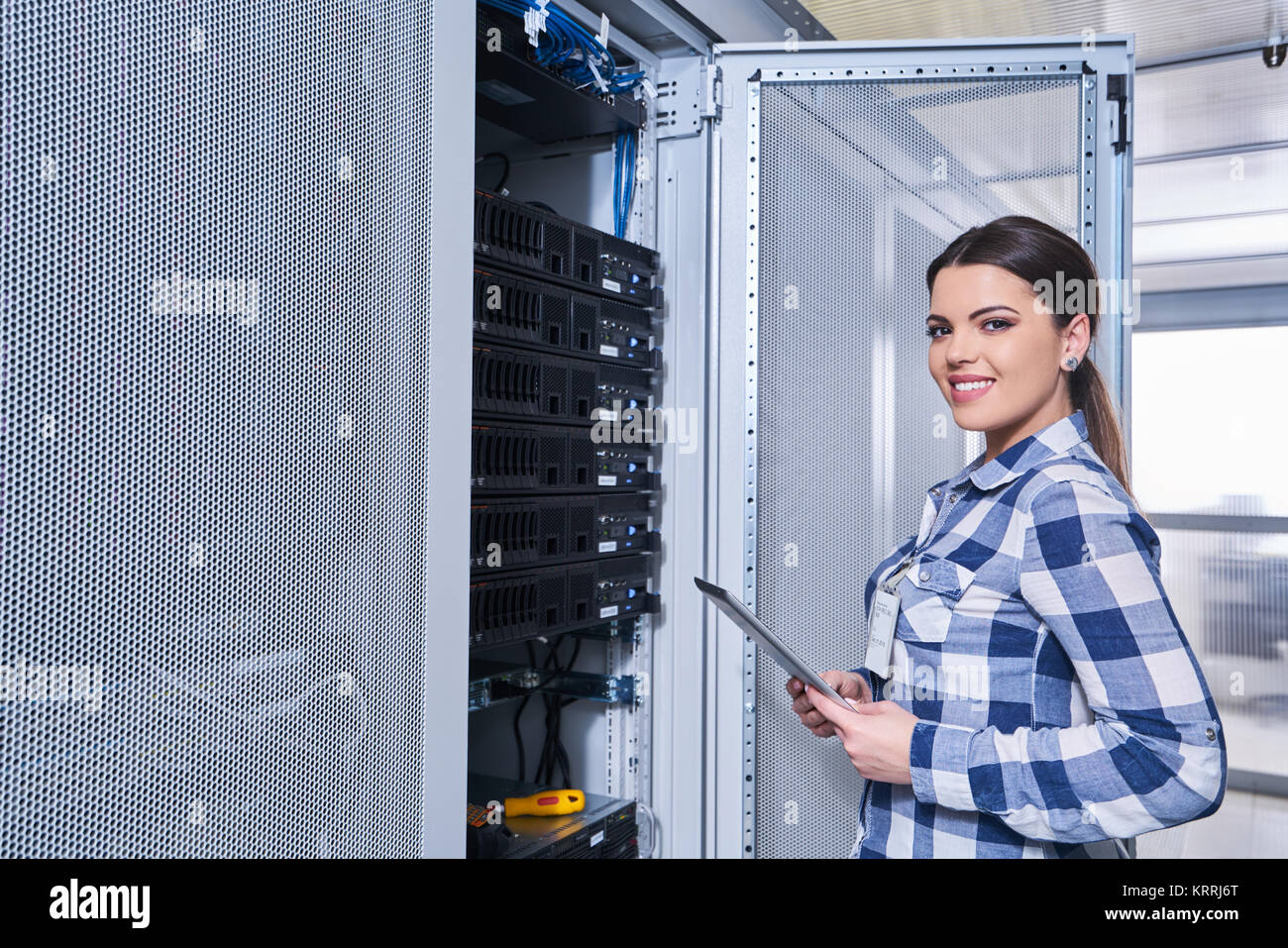 female technician working on server maintenance in white server room ...