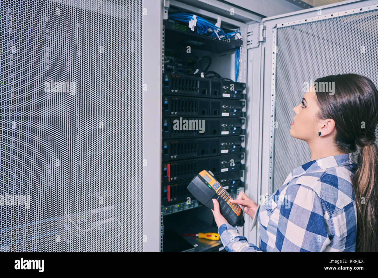 female technician working on server maintenance in white server room ...
