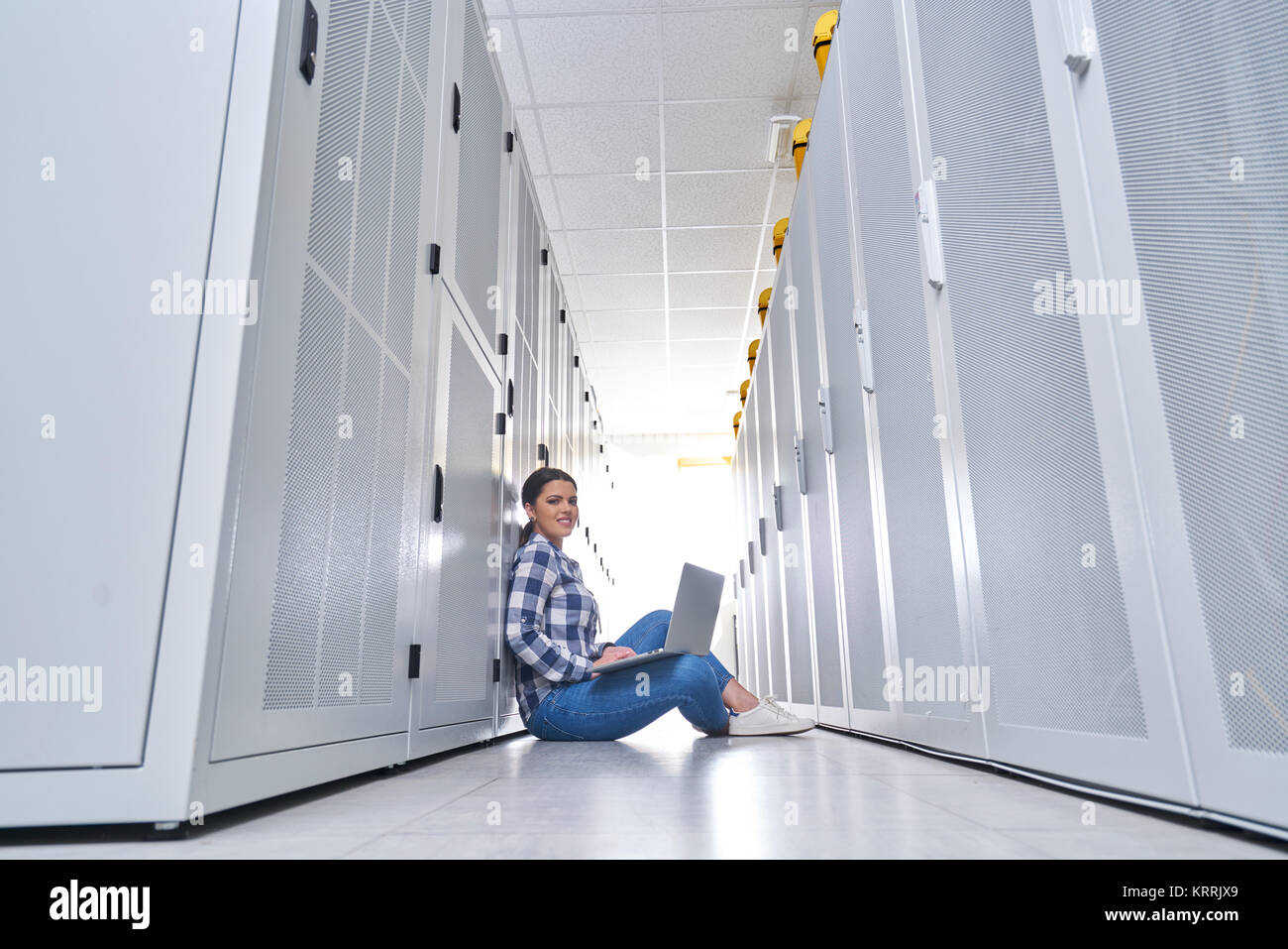female technician working on server maintenance in white server room ...