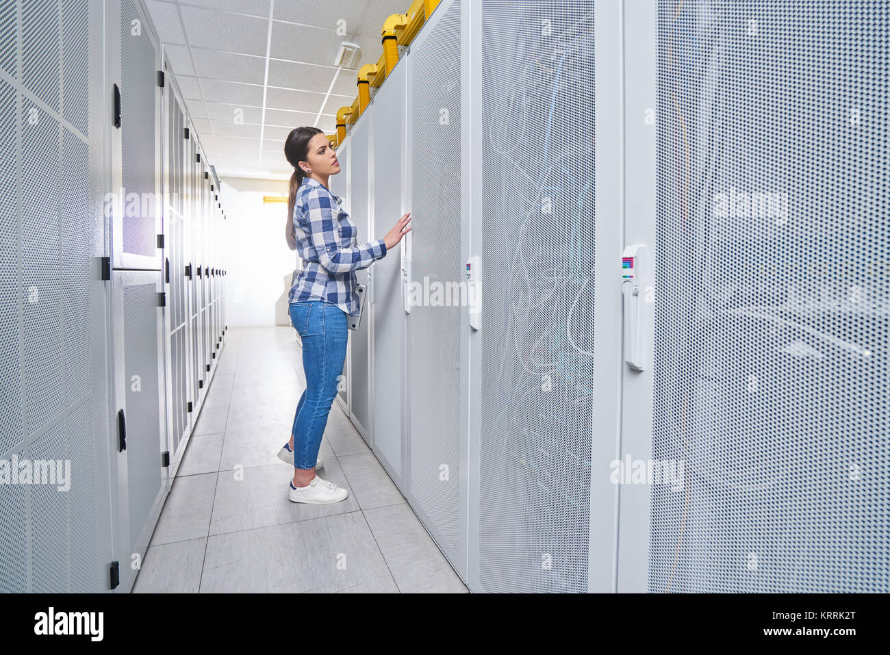 female technician working on server maintenance in white server room ...