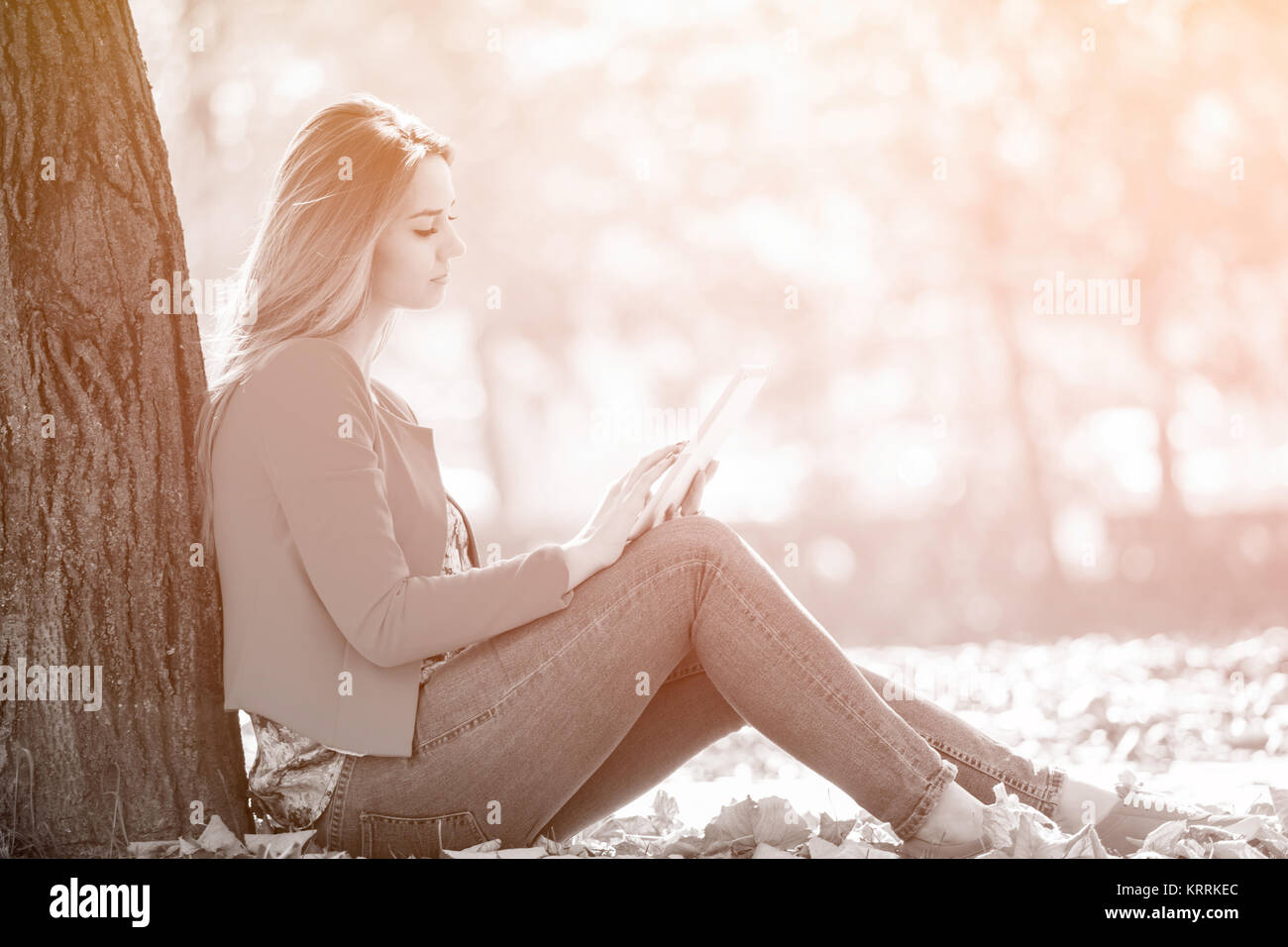 Pretty girl using tablet outside in the park. work, fun, enjoyment ...