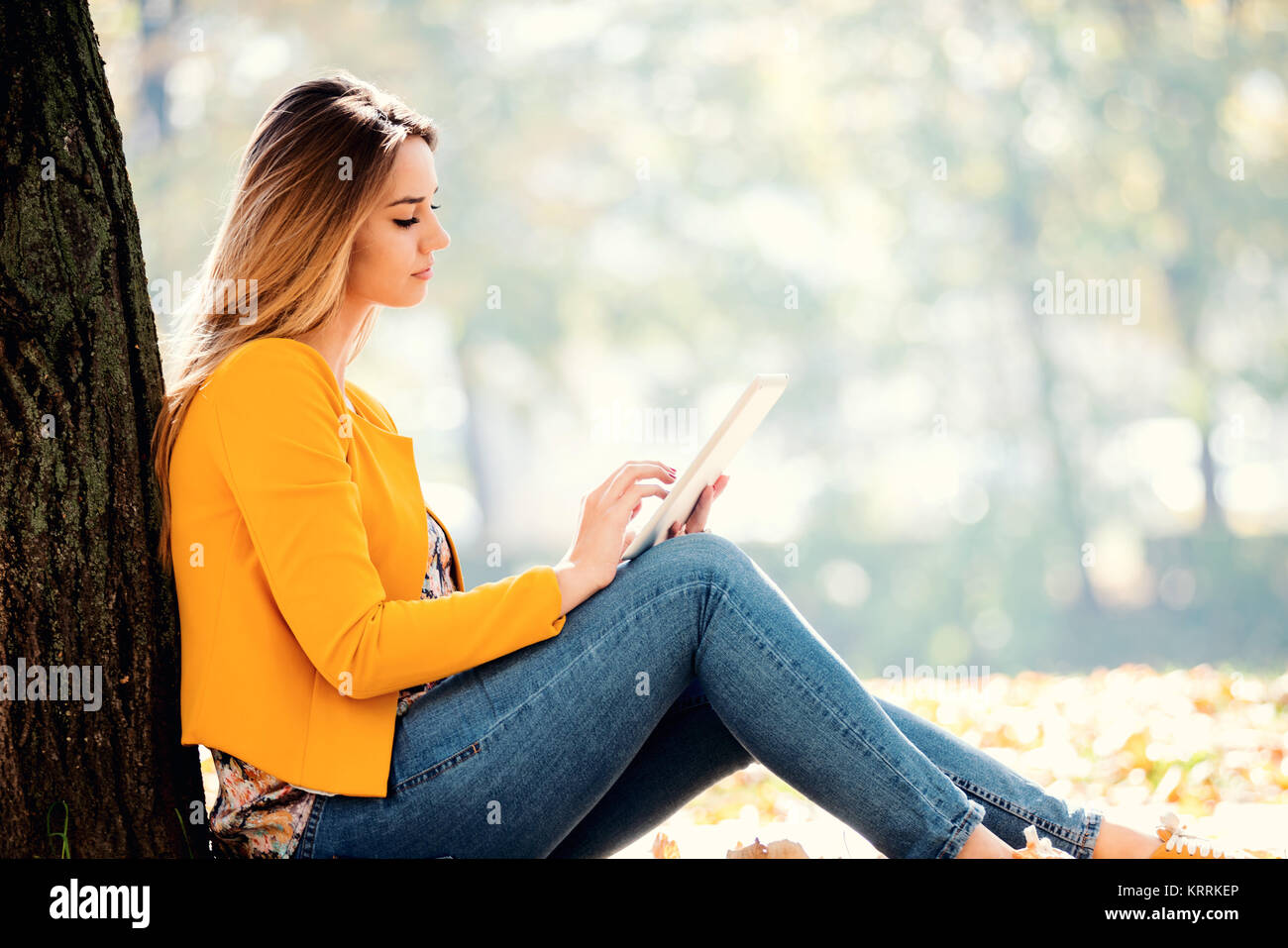 Pretty girl using tablet outside in the park. work, fun, enjoyment ...