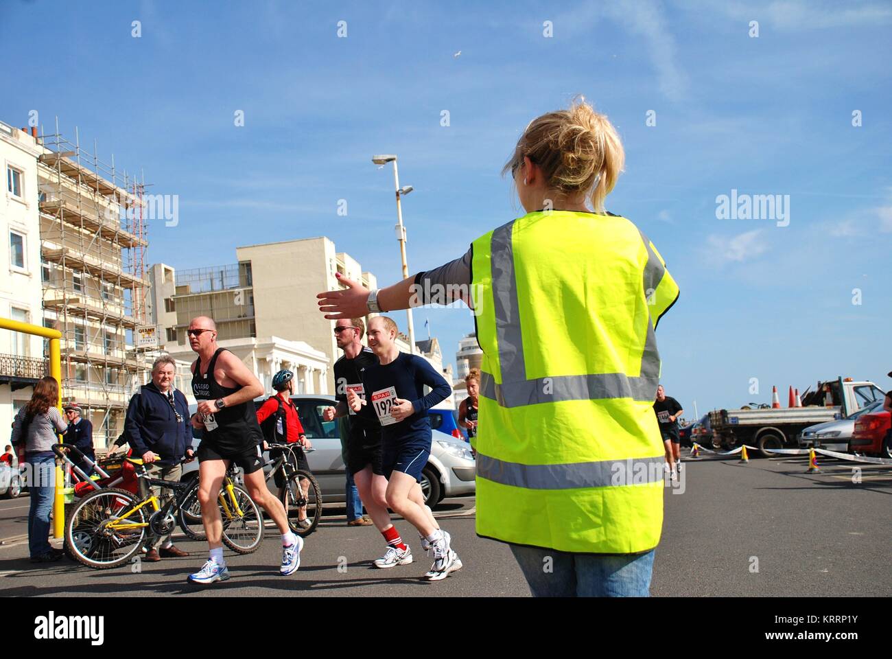 A race marshal directs runners on the seafront during the Hastings Half ...