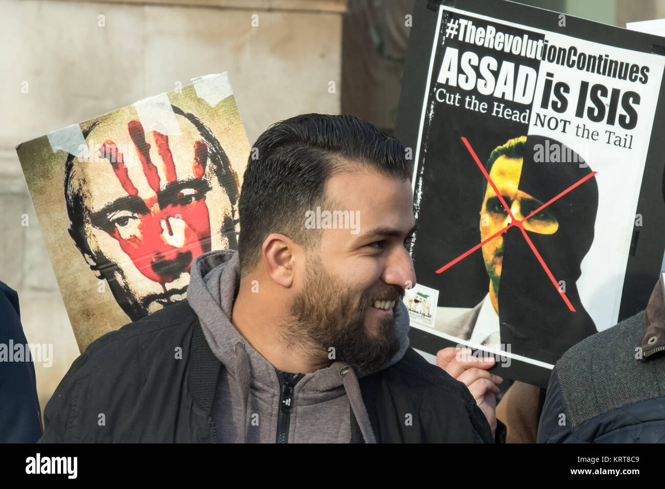 Putin, Assad and a ISIS balaclava on posters behind a protester at the ...