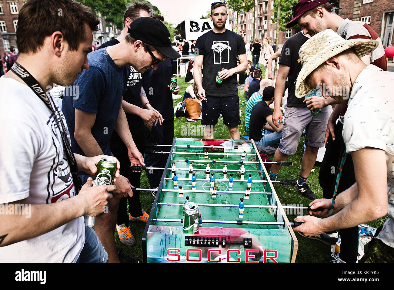 A group of young men are enjoying a game of table foodball in the open ...