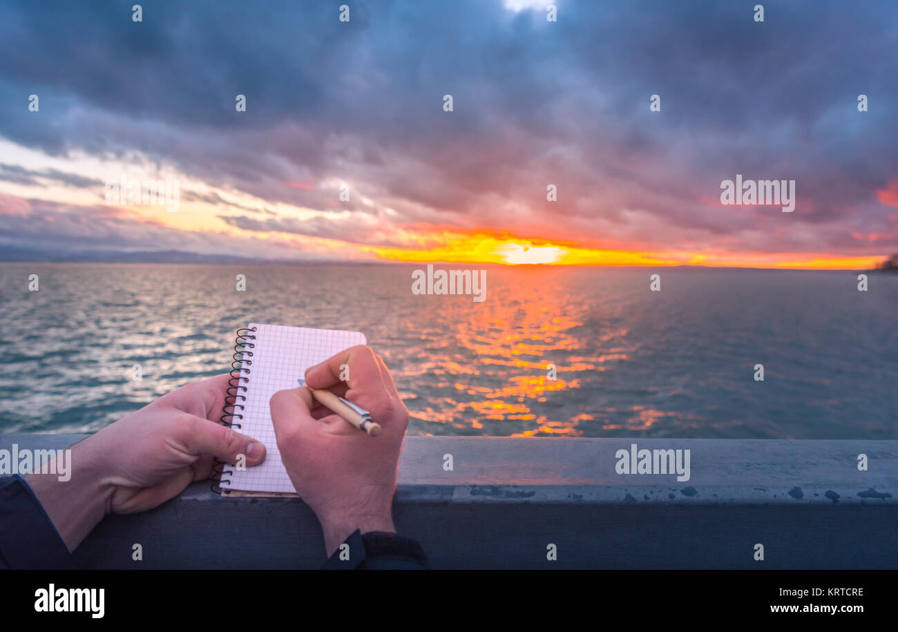 Writing on a notebook at sunset Stock Photo - Alamy