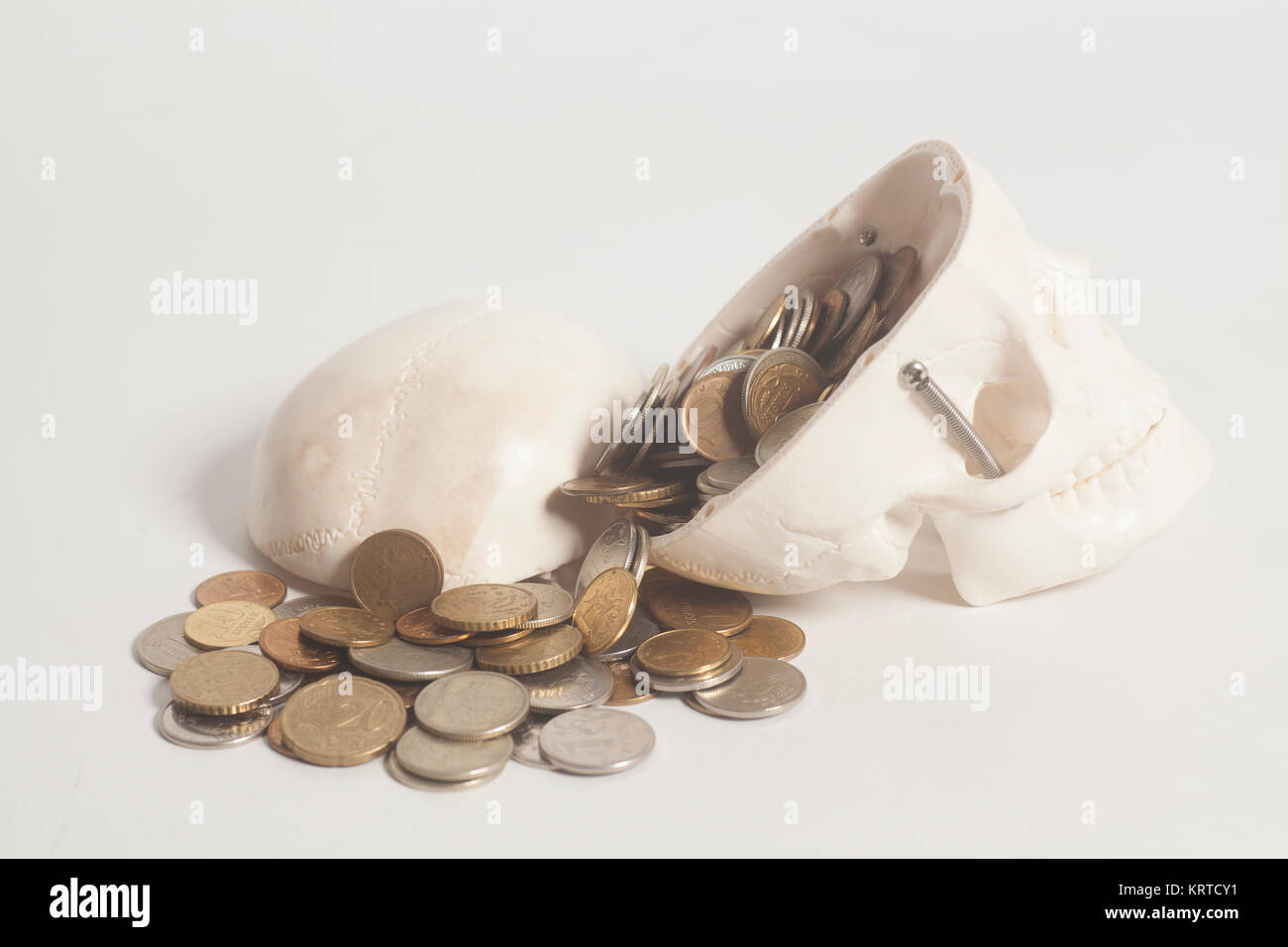 Coins in skulls head on a white background Stock Photo - Alamy
