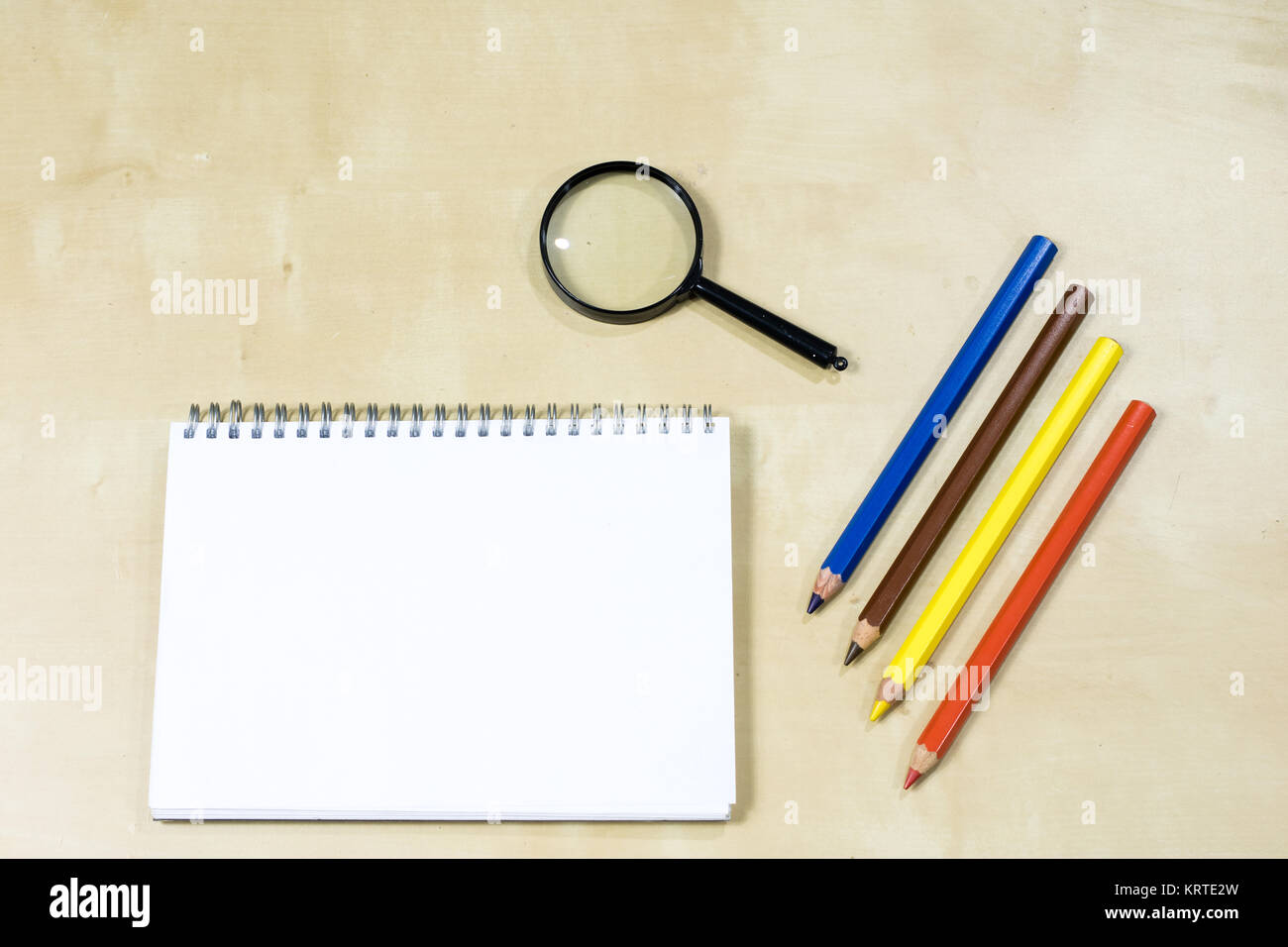 Pencils in a container and magnifier on a wooden table. Drawing ...