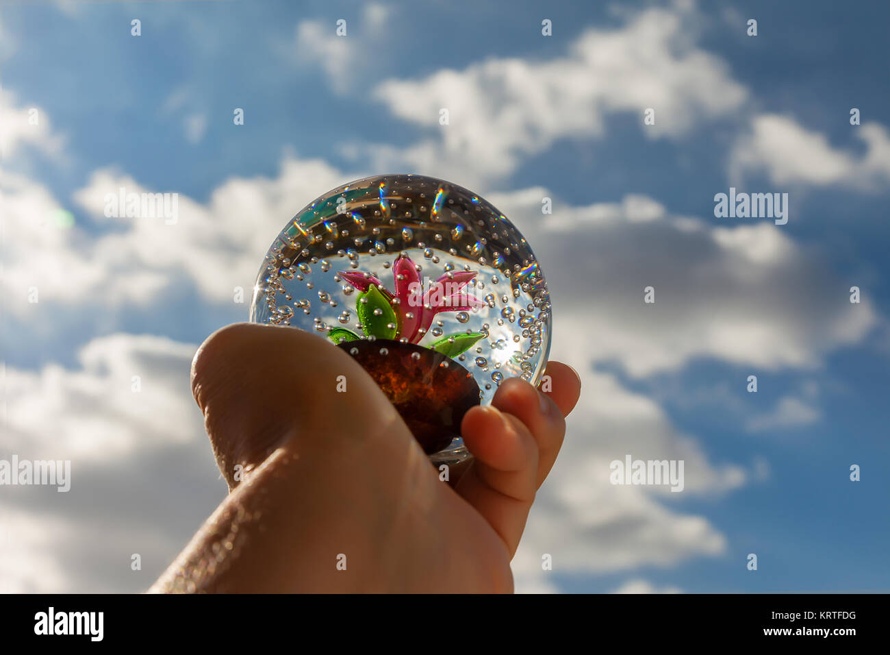 Paperweight. Hand holding a glass paperweight with clouds in the ...