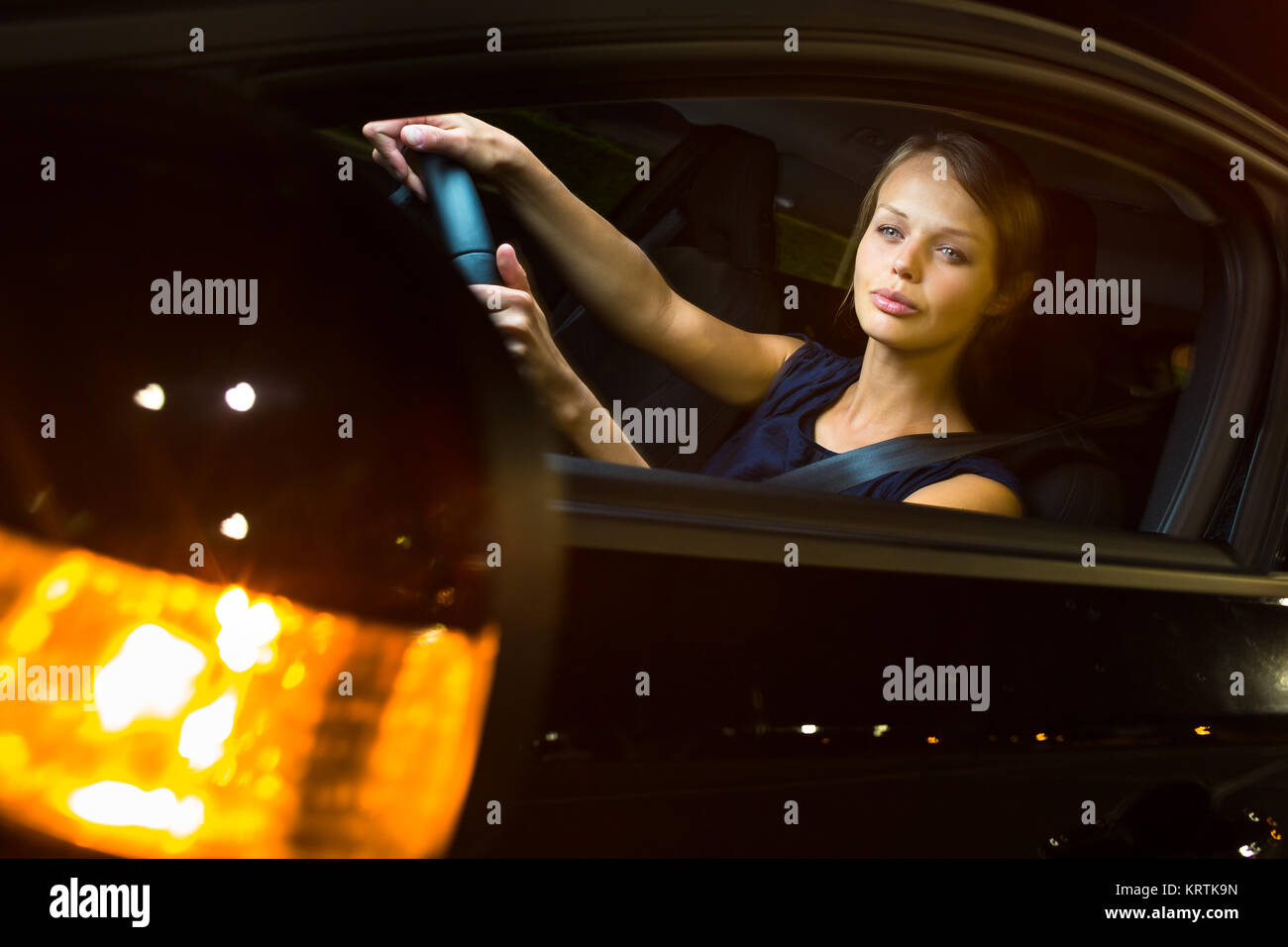 Driving a car at night - pretty, young woman driving her modern car at ...