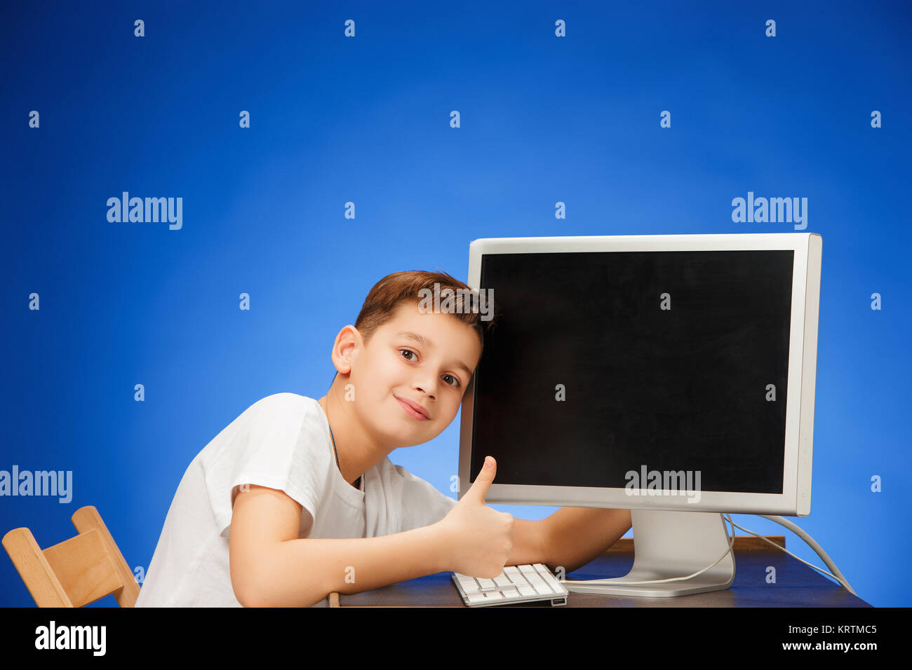 School-age boy sitting in front of the monitor laptop at studio Stock ...