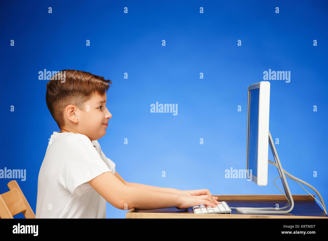 School-age boy sitting in front of the monitor laptop at studio Stock ...