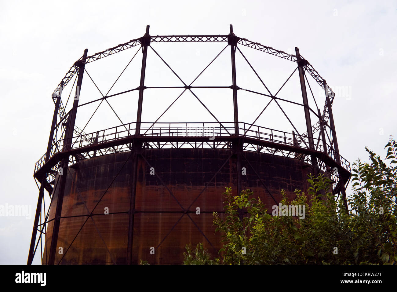 Very old and rusty gas storage tank ruin with tree Stock Photo - Alamy