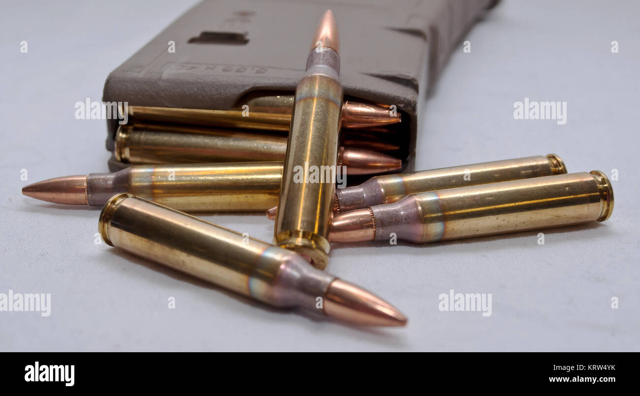 Several .223 caliber rounds and a loaded magazine on a white background ...