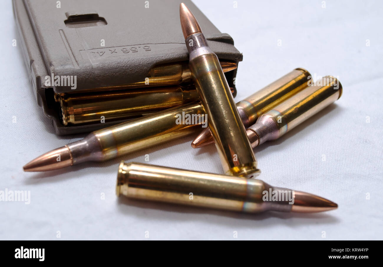 Several .223 caliber rounds and a loaded magazine on a white background ...