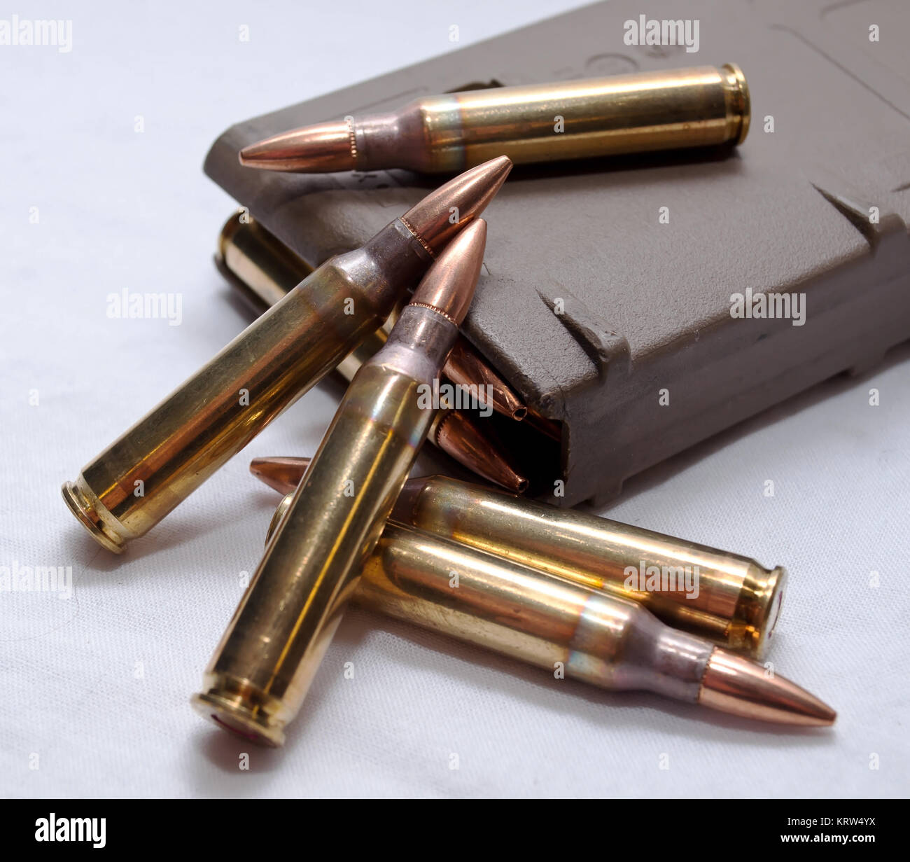 Several .223 caliber rounds and a loaded magazine on a white background ...