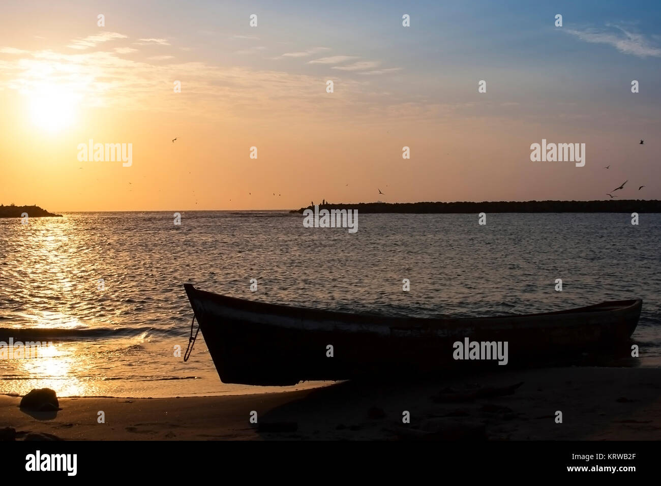 Canoe on the sand next to the sea at sunset Stock Photo - Alamy