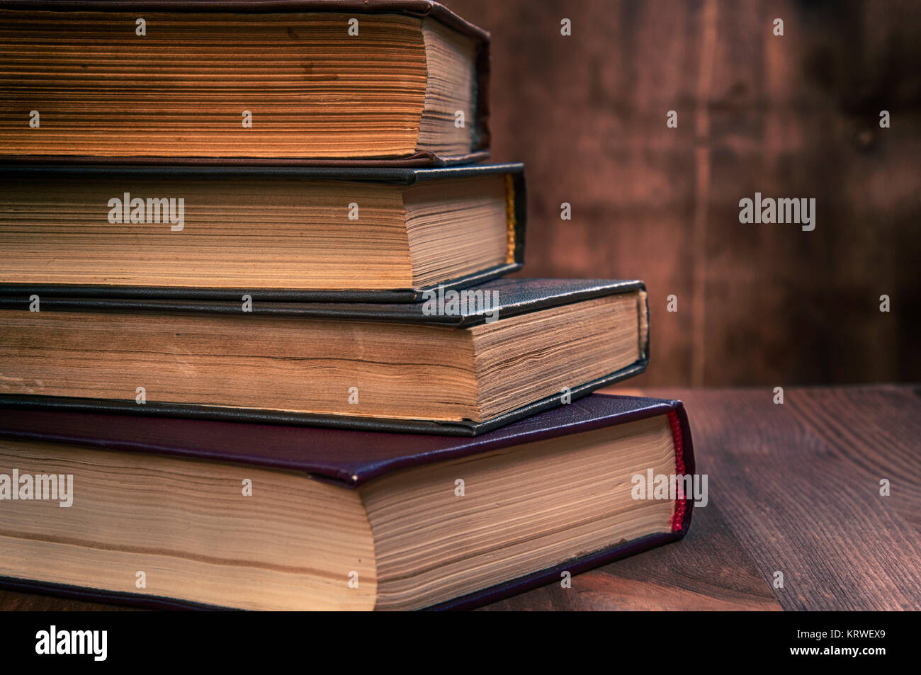 stack of old books on a brown wooden background Stock Photo - Alamy