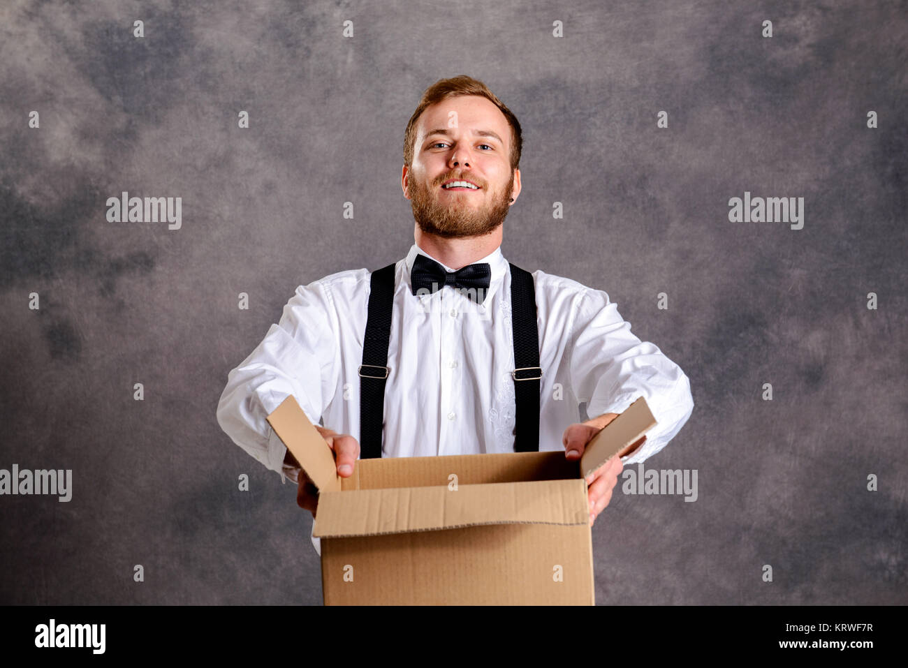 young man opening a package in front of gray background Stock Photo - Alamy