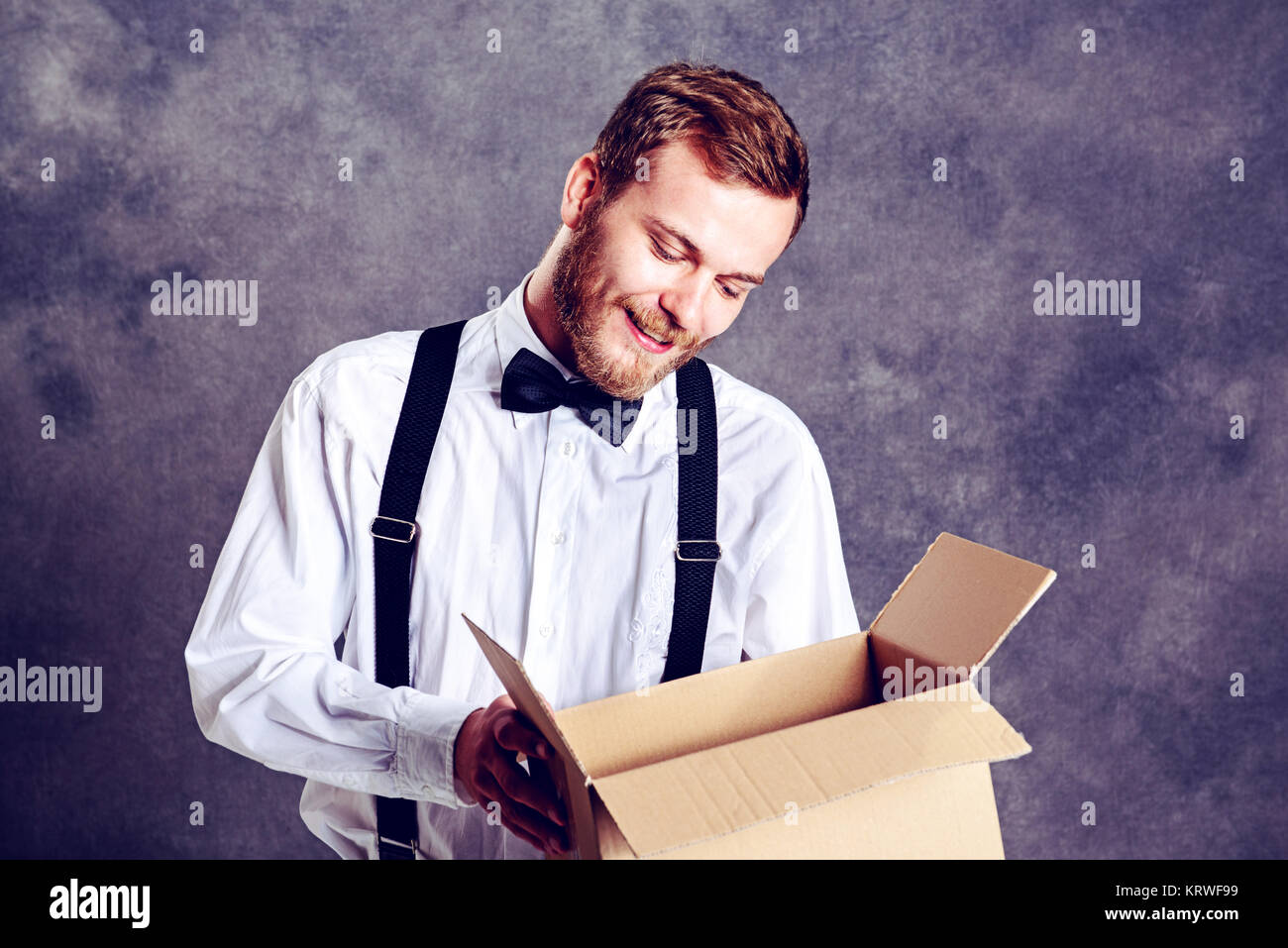 young man opening a package in front of gray background Stock Photo - Alamy