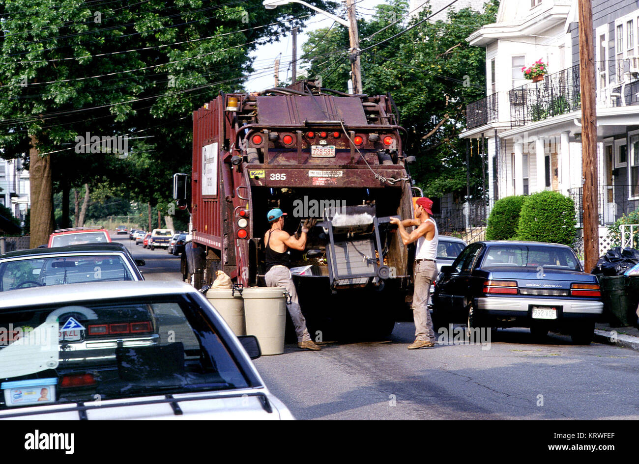Garbage men dump garbage into a garbage truck in an American city in ...