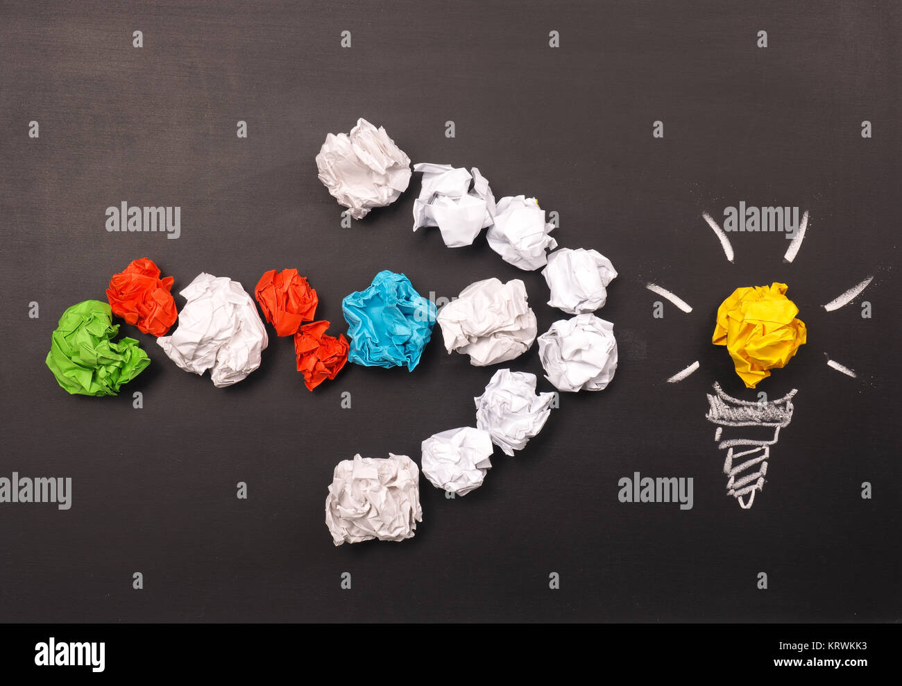 Arrow and light bulb of different crumpled paper as many ideas on a ...