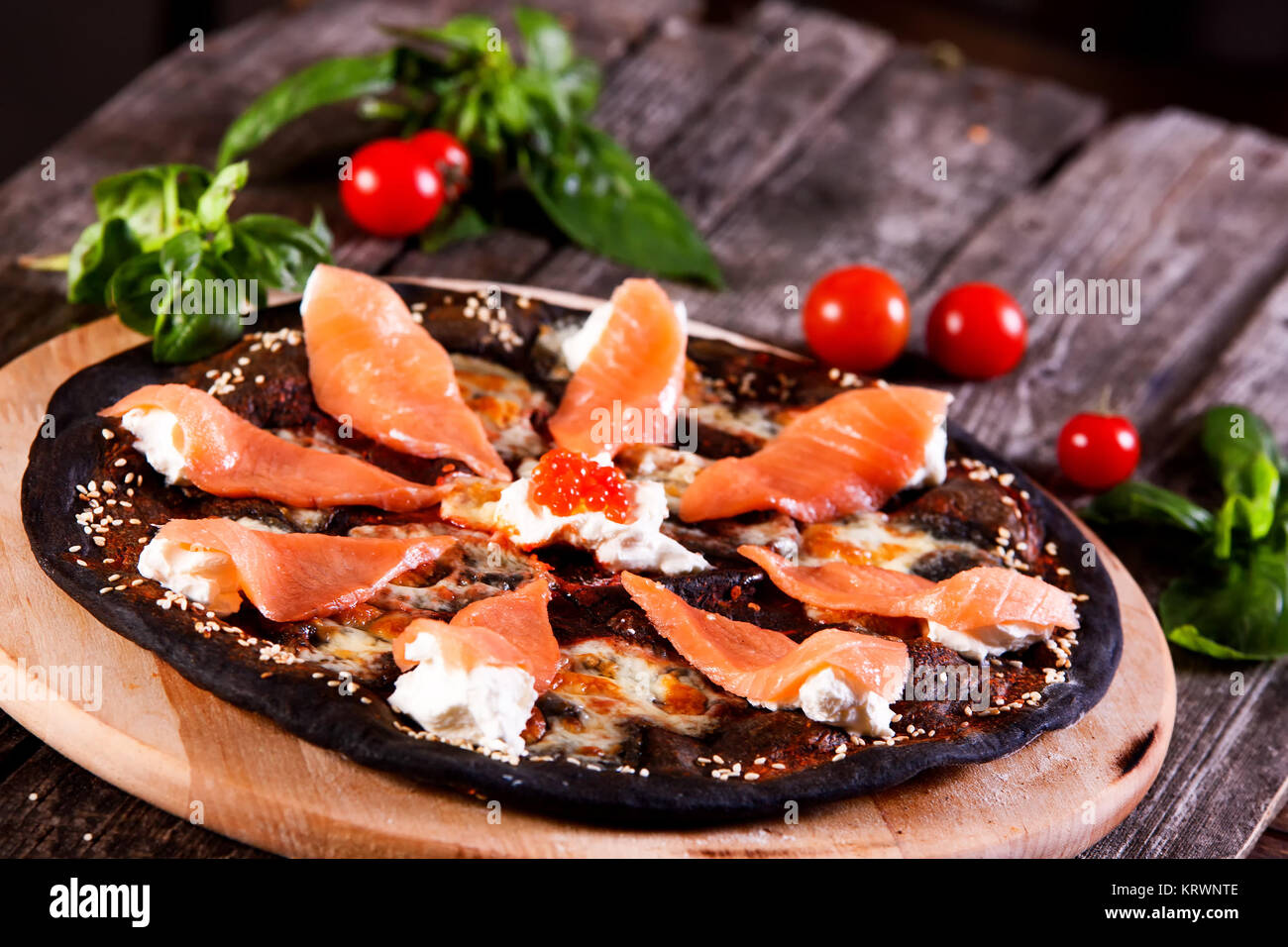 Black pizza with red fish salmon and cream cheese Stock Photo - Alamy