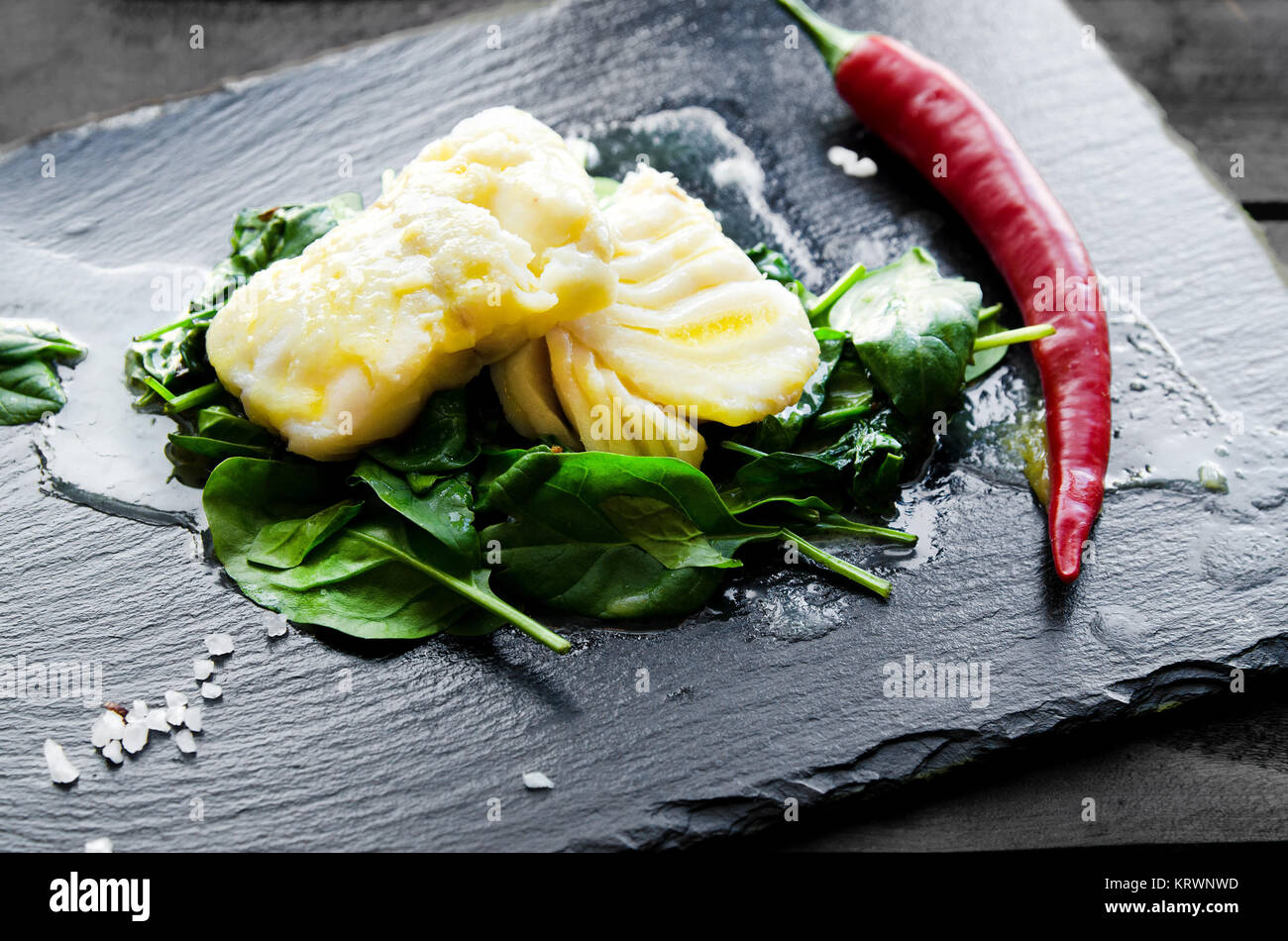 Fish fillet with chili on black background Stock Photo - Alamy