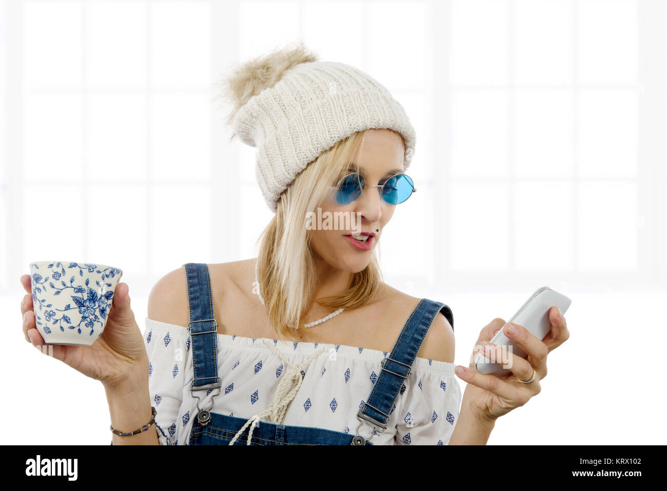pretty blond woman with a cup of tea and phone Stock Photo - Alamy