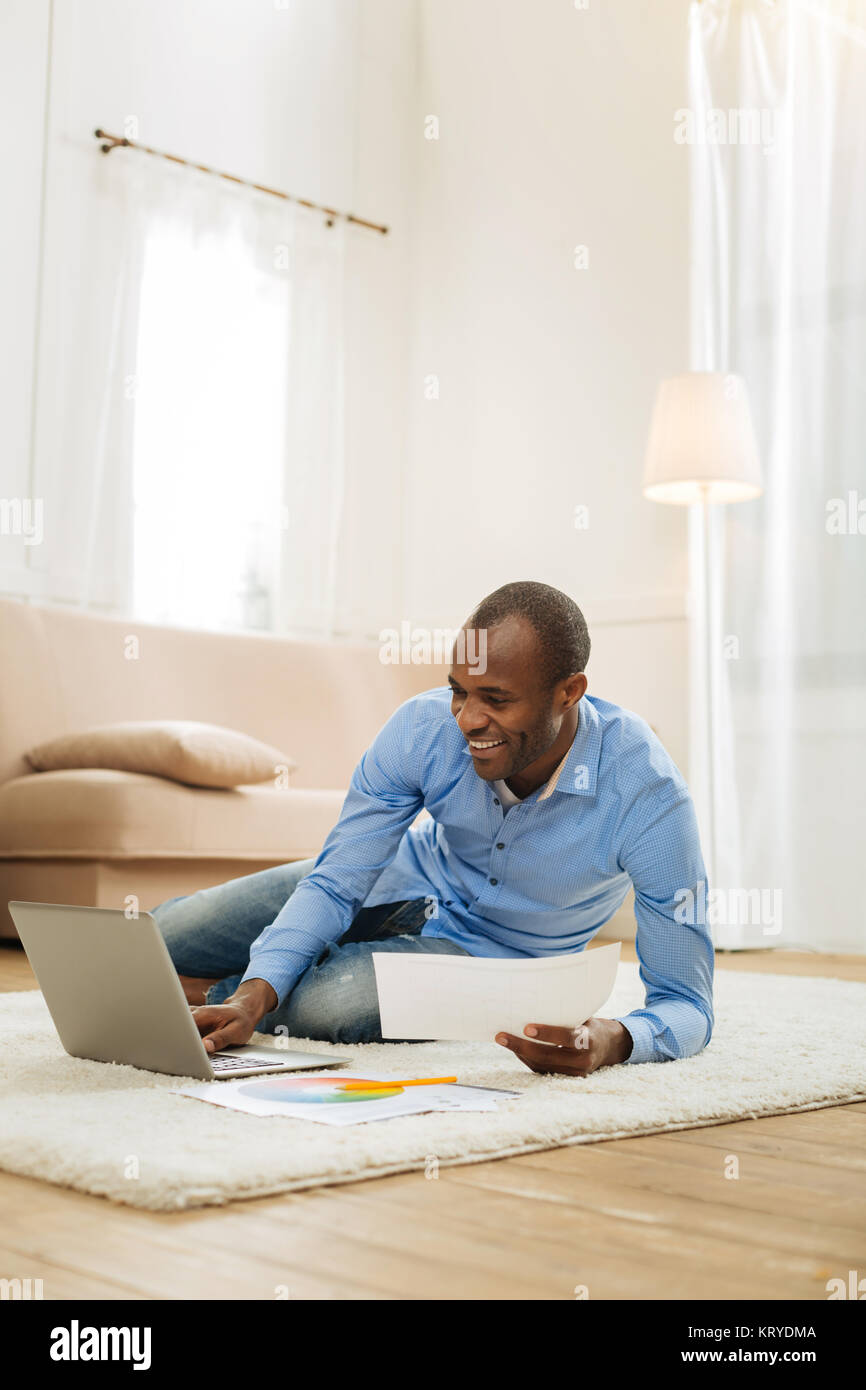 Inspired man working on his laptop on the carpet Stock Photo - Alamy