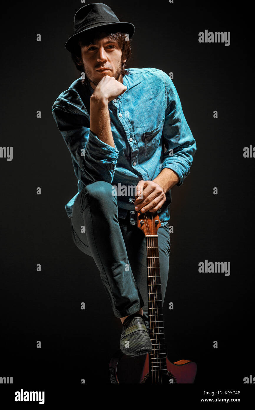 Cool guy standing with guitar on dark background Stock Photo - Alamy