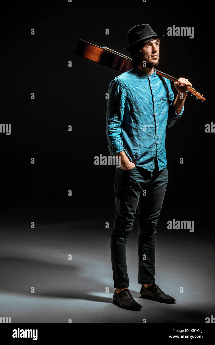 Cool guy standing with guitar on dark background Stock Photo - Alamy