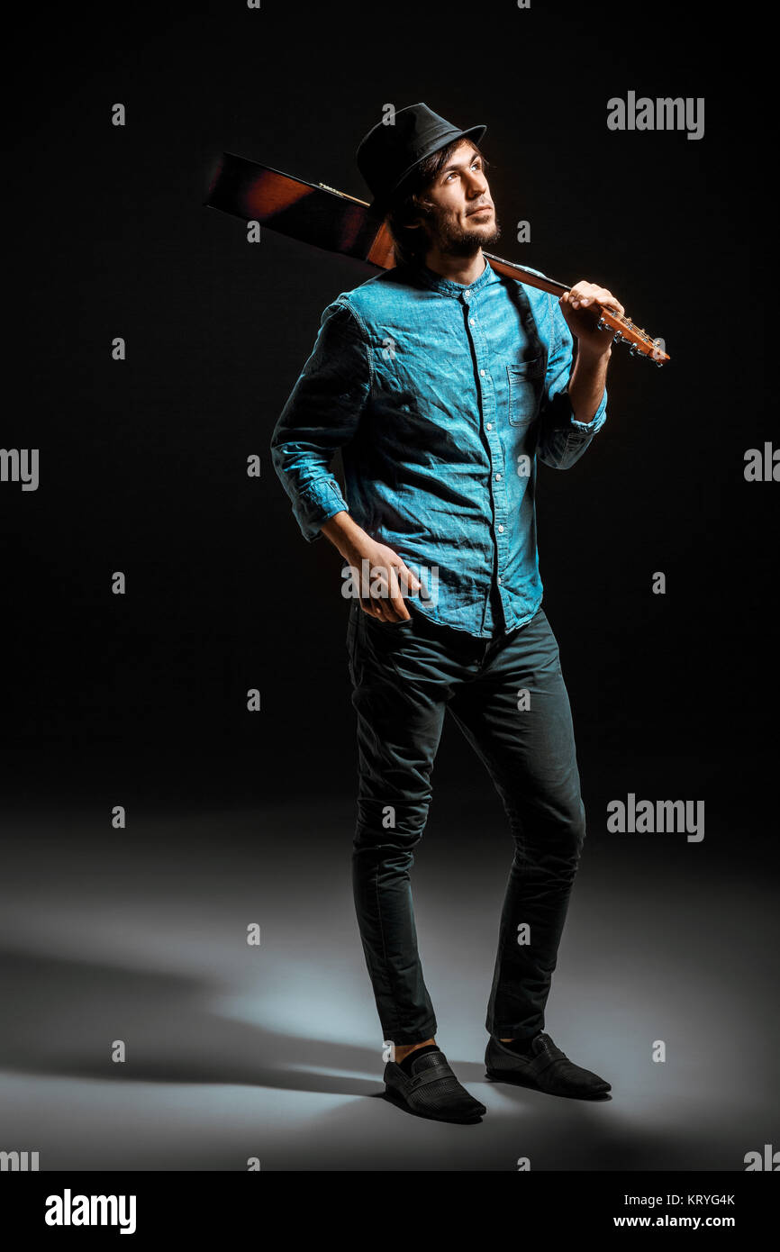 Cool guy standing with guitar on dark background Stock Photo - Alamy