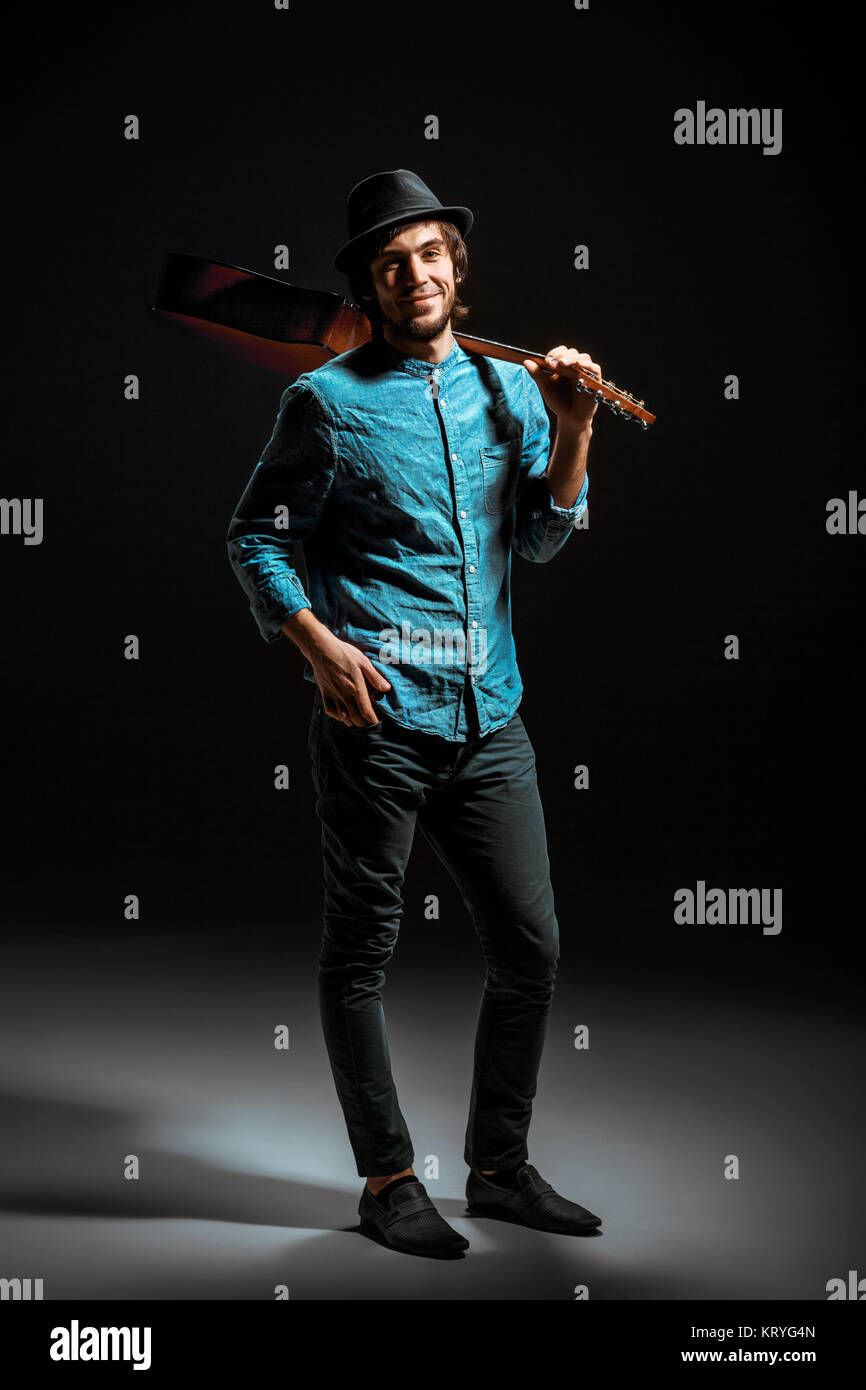 Cool guy standing with guitar on dark background Stock Photo - Alamy