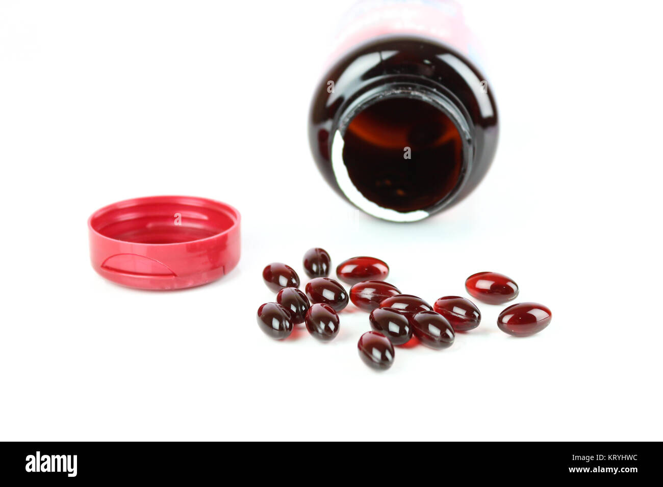 Red gel capsules isolated on white background with a bottle at the ...
