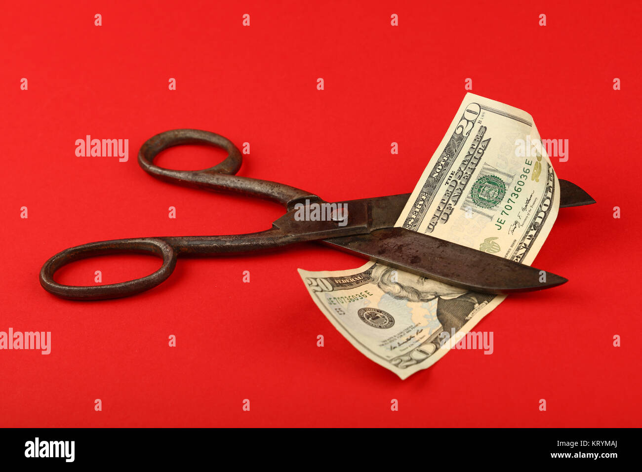 Scissors cut US dollars over red background Stock Photo - Alamy