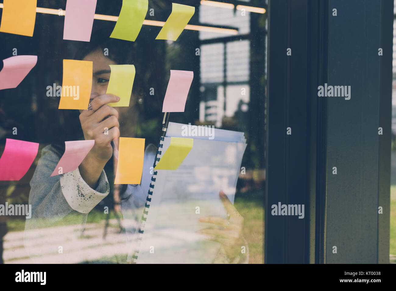 Businesswoman hold adhesive notes on glass wall in meeting room at ...