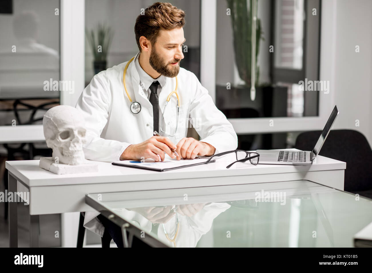 Portrait of an elegant senior doctor in medical gown working with ...