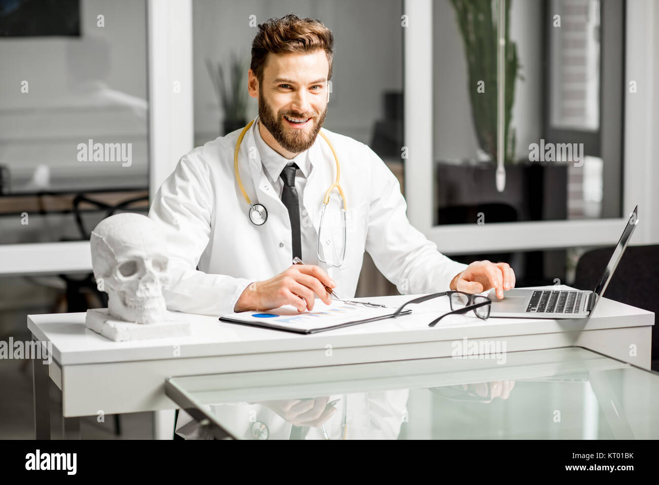 Portrait of an elegant senior doctor in medical gown working with ...