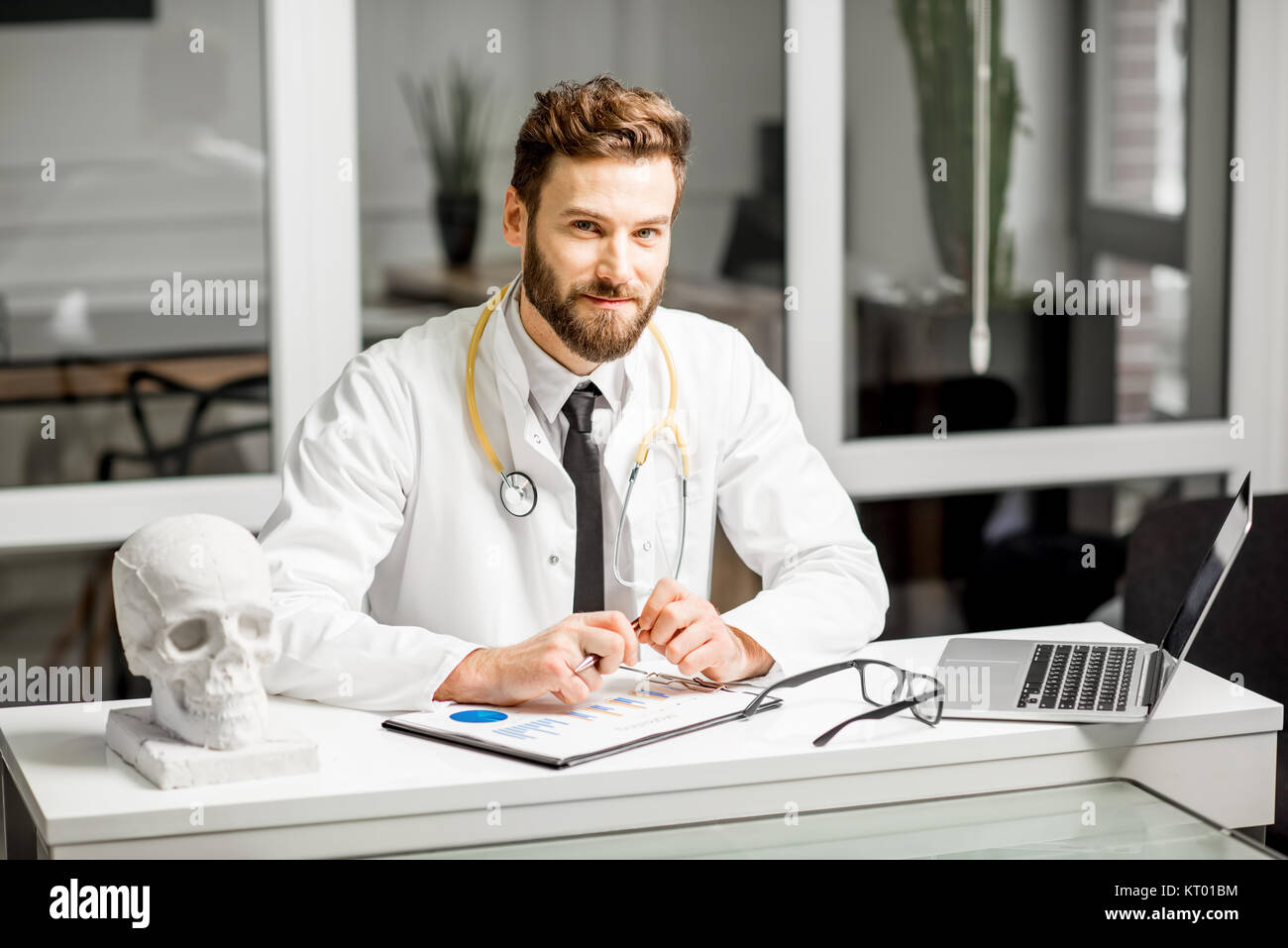 Portrait of an elegant senior doctor in medical gown working with ...