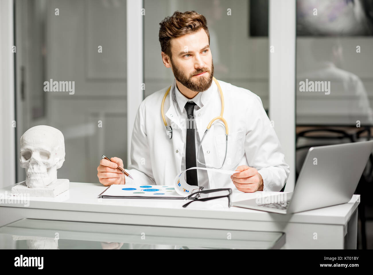Portrait of an elegant senior doctor in medical gown working with ...