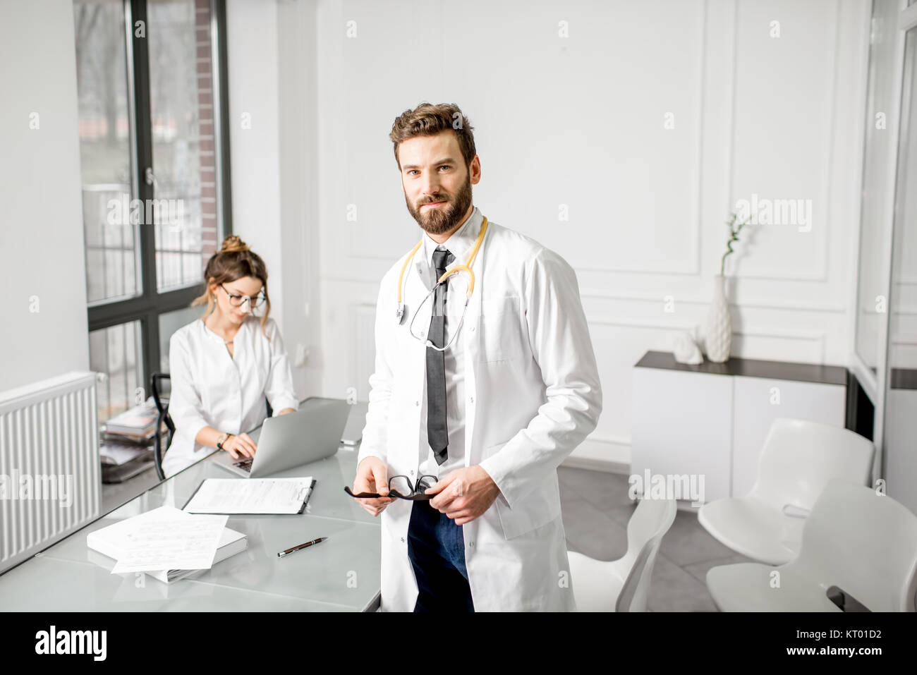 Portrait of an elegant senior doctor in medical gown with young female ...
