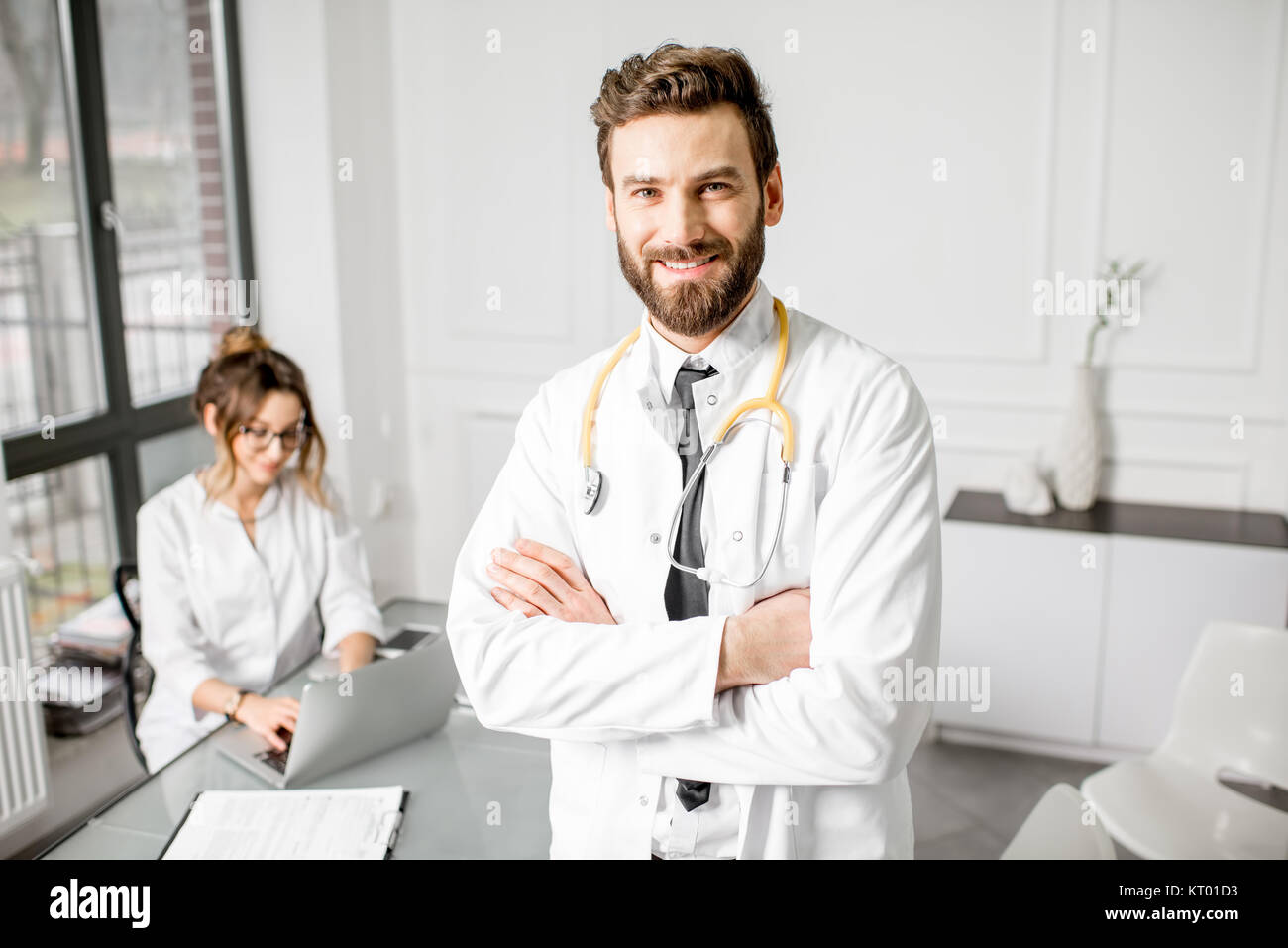 Portrait of an elegant senior doctor in medical gown with young female ...