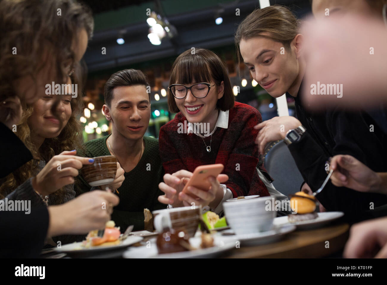 Group of positive teens use a smartphone and spend time in a cafe Stock ...