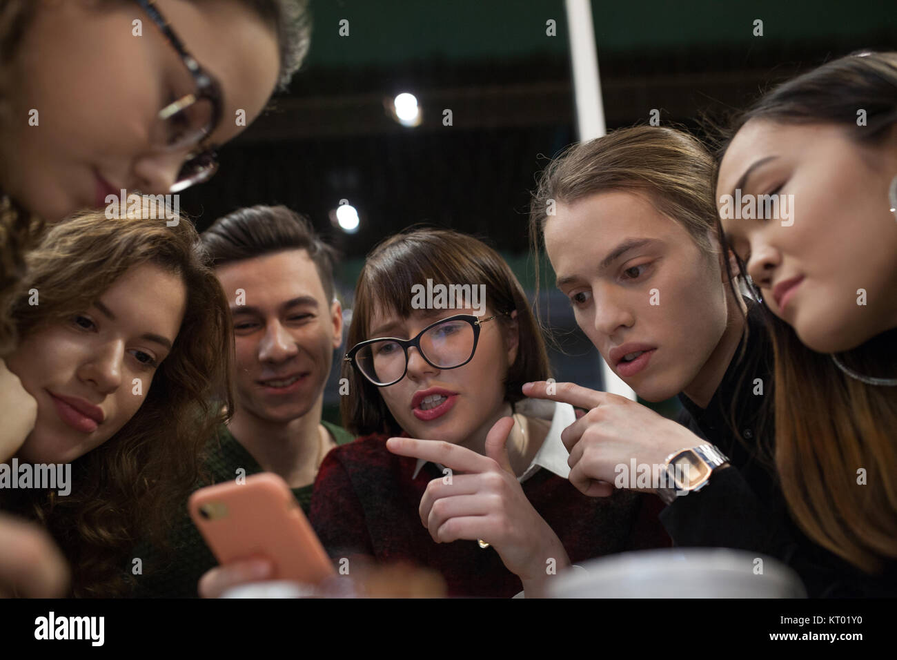 Group of positive teens use a smartphone and spend time in a cafe Stock ...