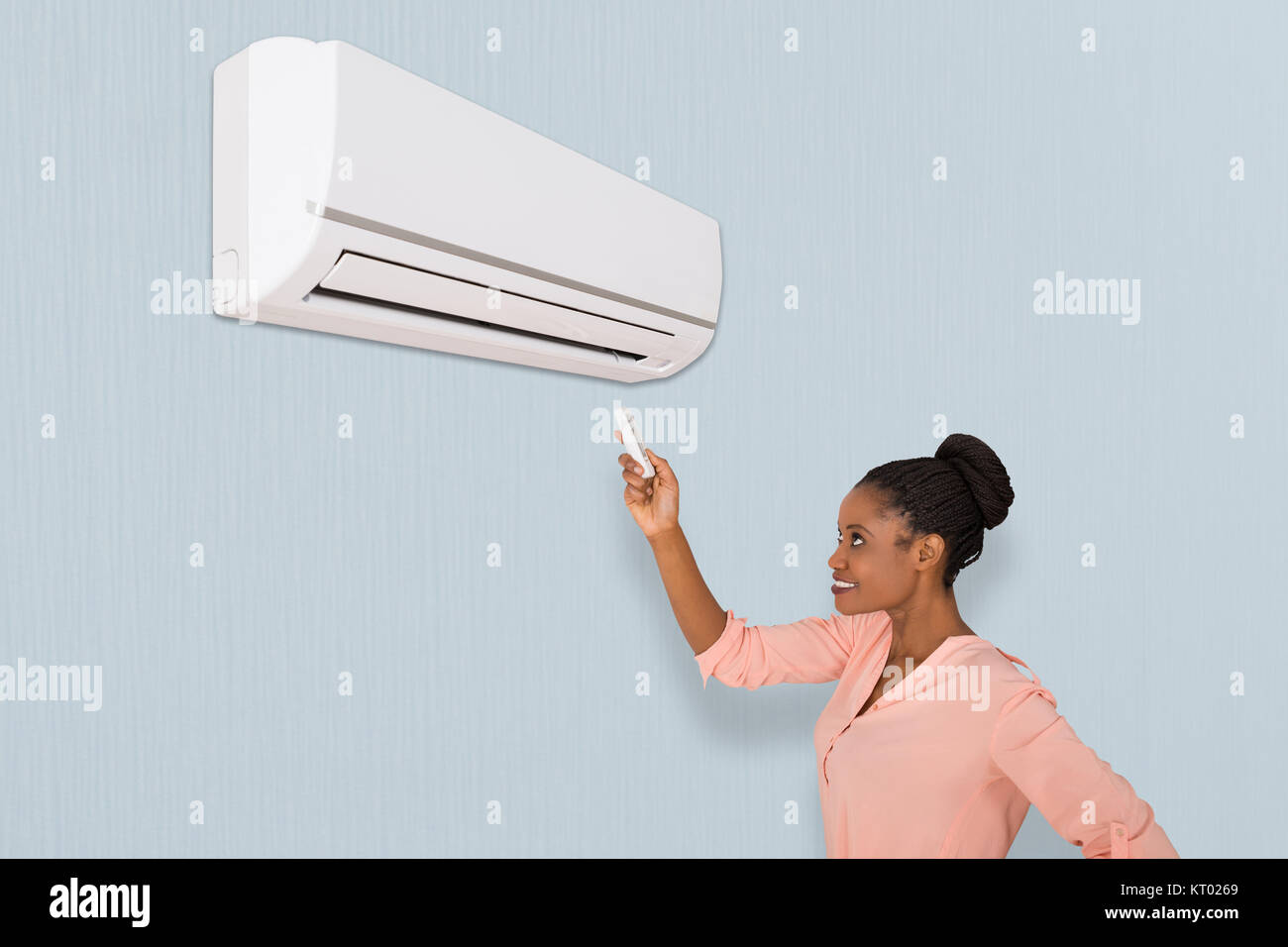 Smiling Woman Operating Air Conditioner Stock Photo - Alamy
